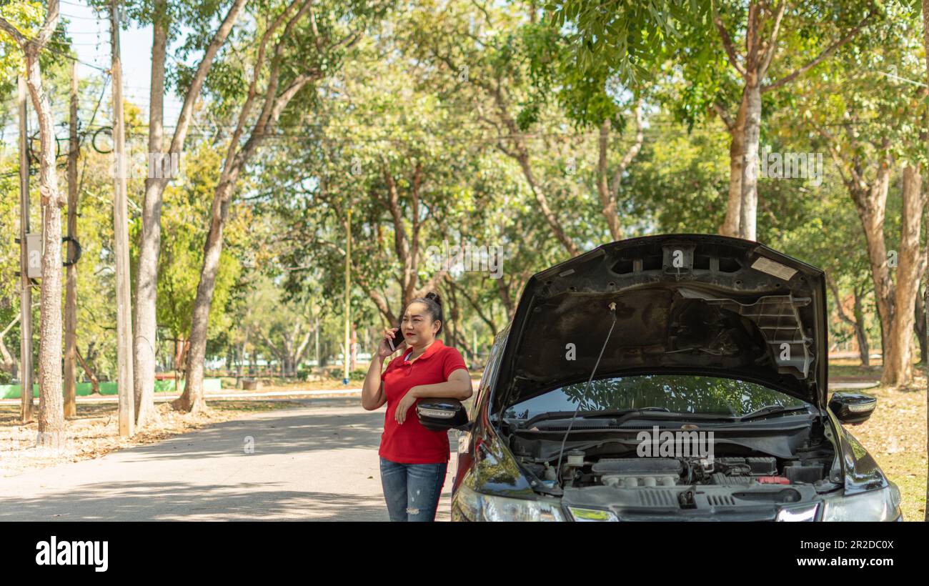 An anxious man stands and inspects a broken-down car in a rural ...