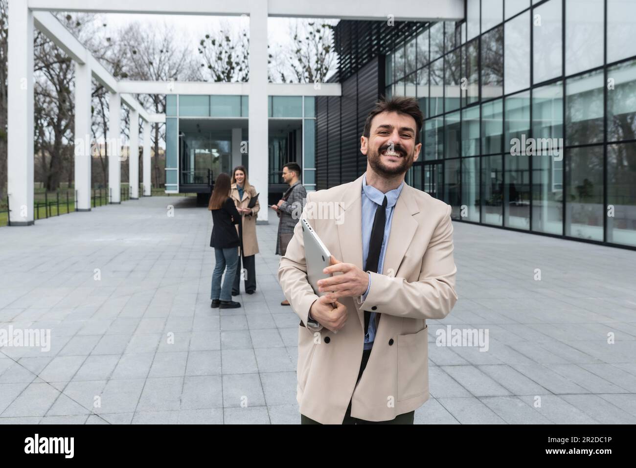Young business man welcomes new employees in front of the office ...