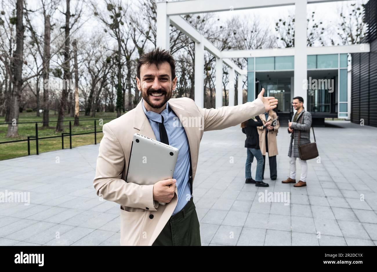 Young business man welcomes new employees in front of the office ...
