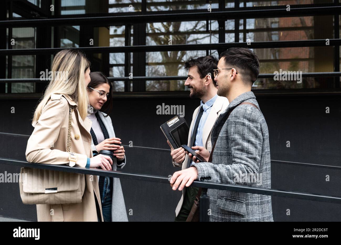 Young businesspeople standing in front of office building talking ...