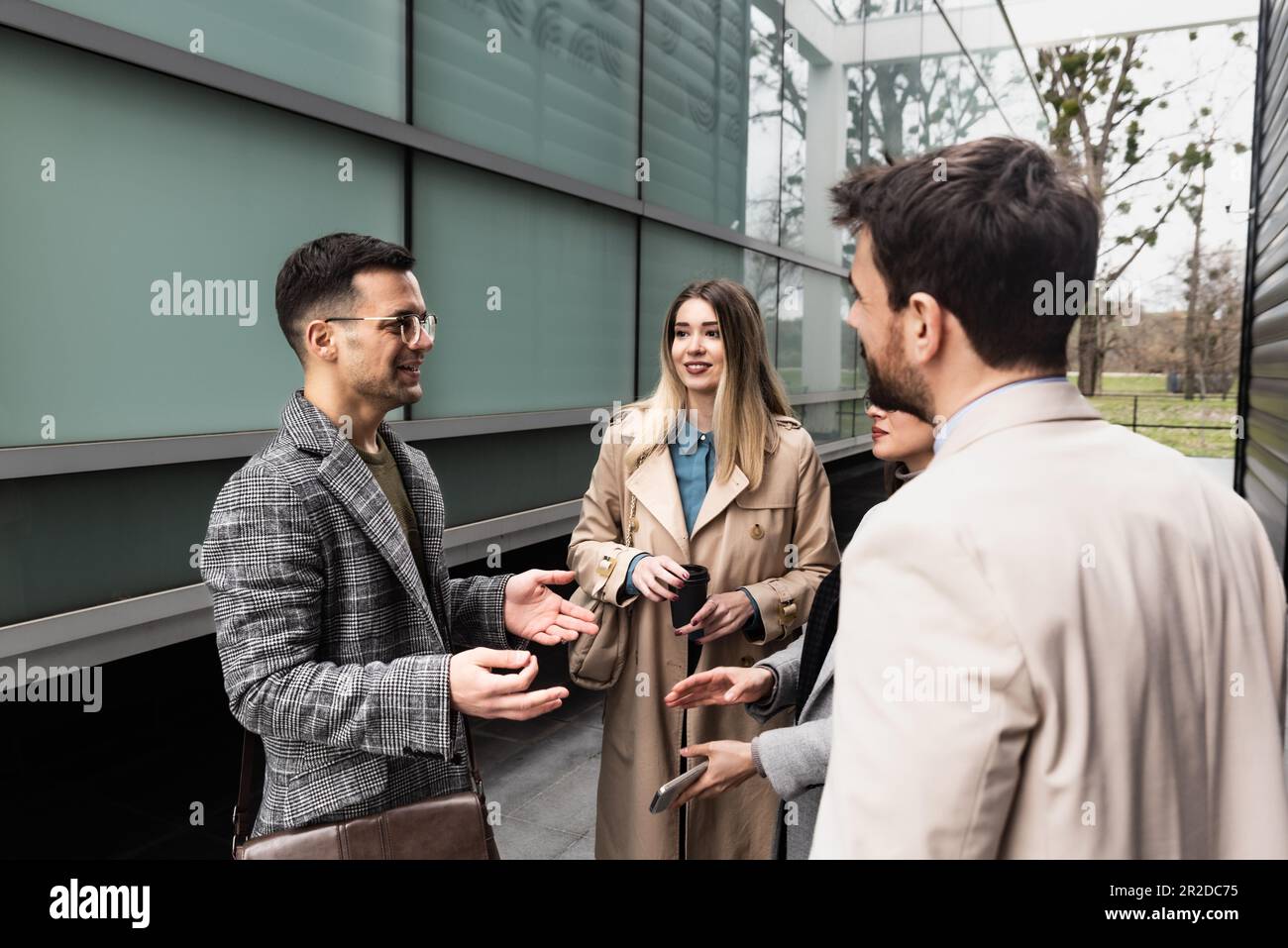 Young businesspeople standing in front of office building talking ...