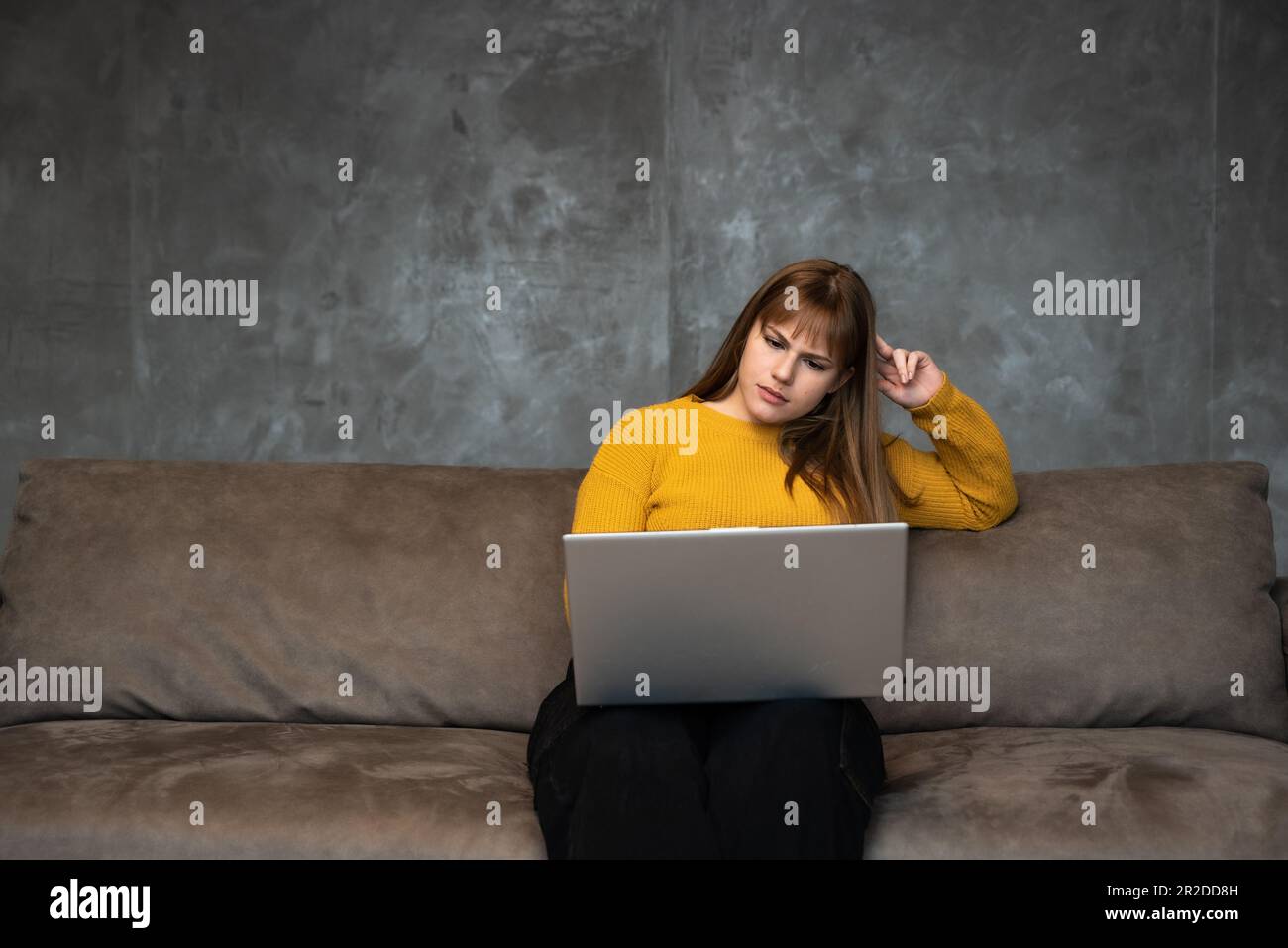 Young freelance business woman sitting on sofa with laptop working late ...