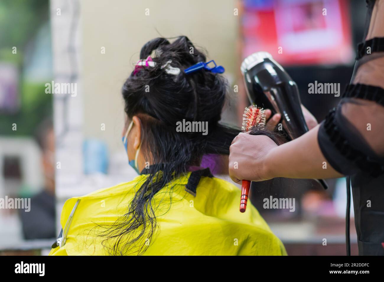 professional woman hairdresser wearing face mask holding hair dryer and ...