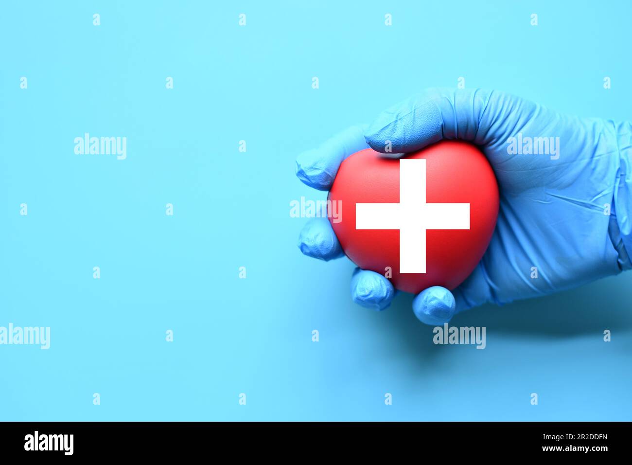 A red cross is a symbol of medical health. Hand holding a heart and on ...