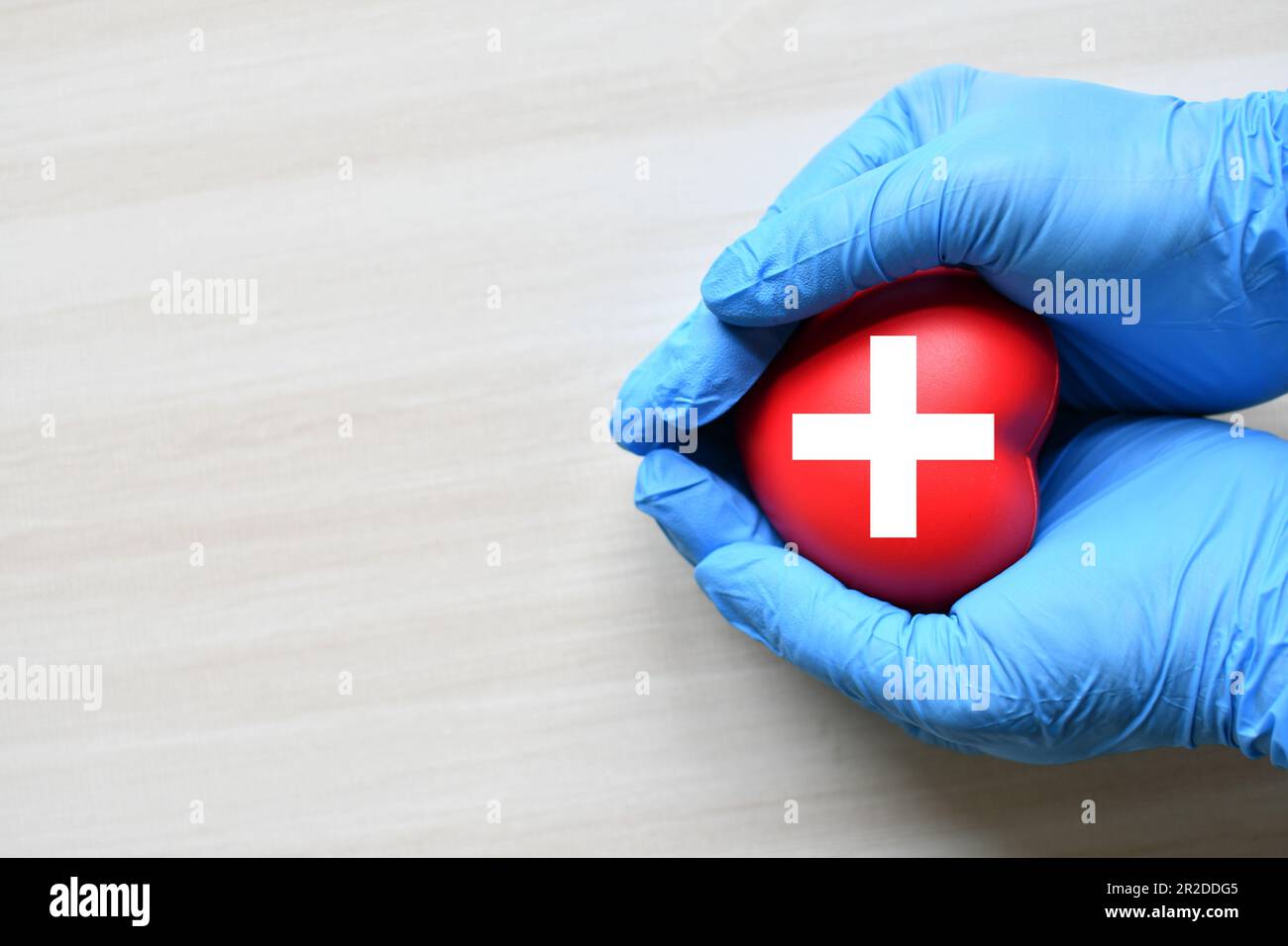 A red cross is a symbol of medical health. Hand holding a heart and on ...
