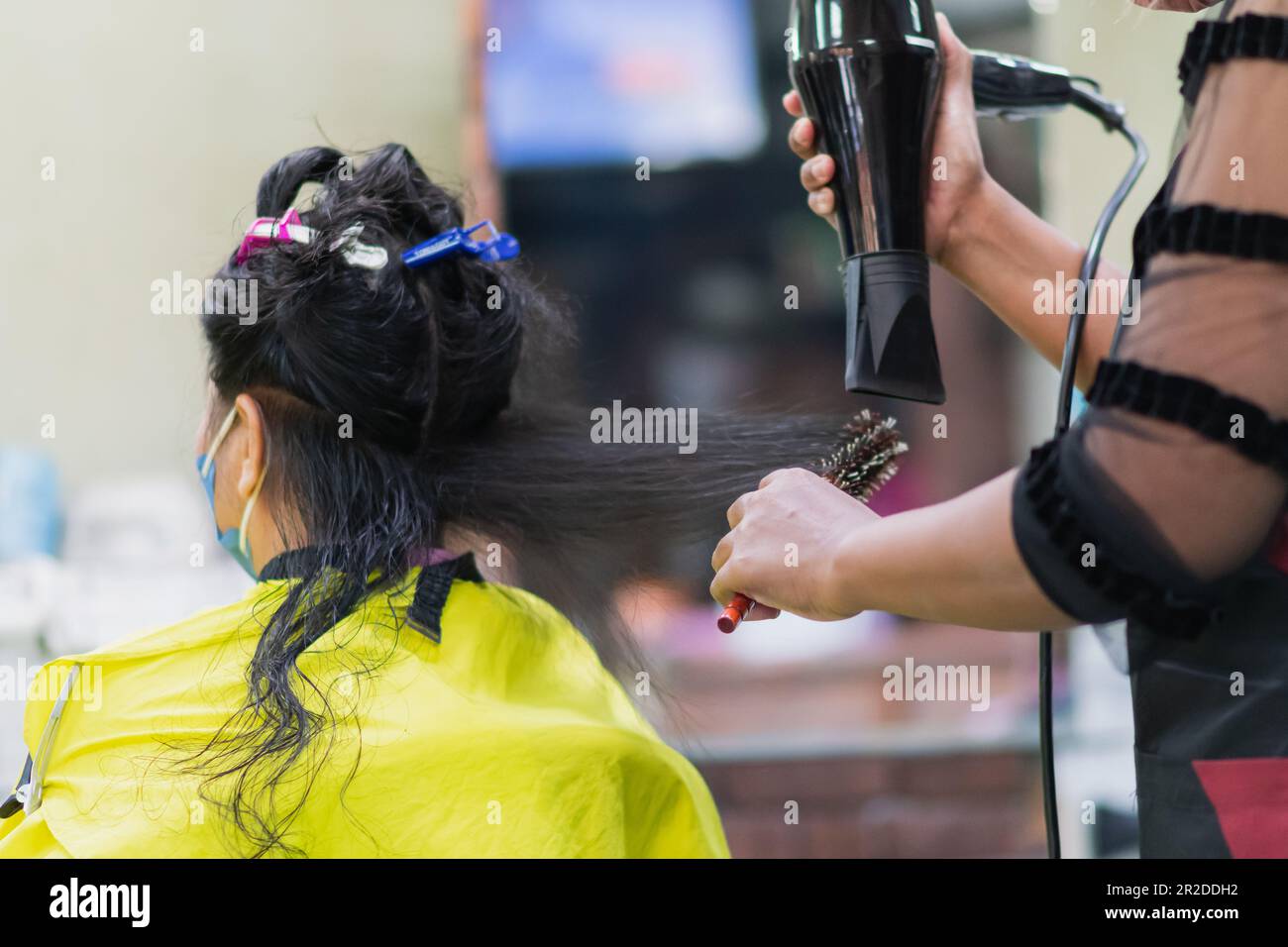 professional woman hairdresser wearing face mask holding hair dryer and ...