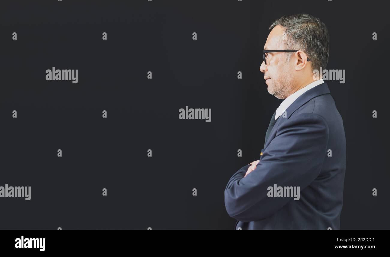 A businessman in a black suit stands facing forward and looks forward ...