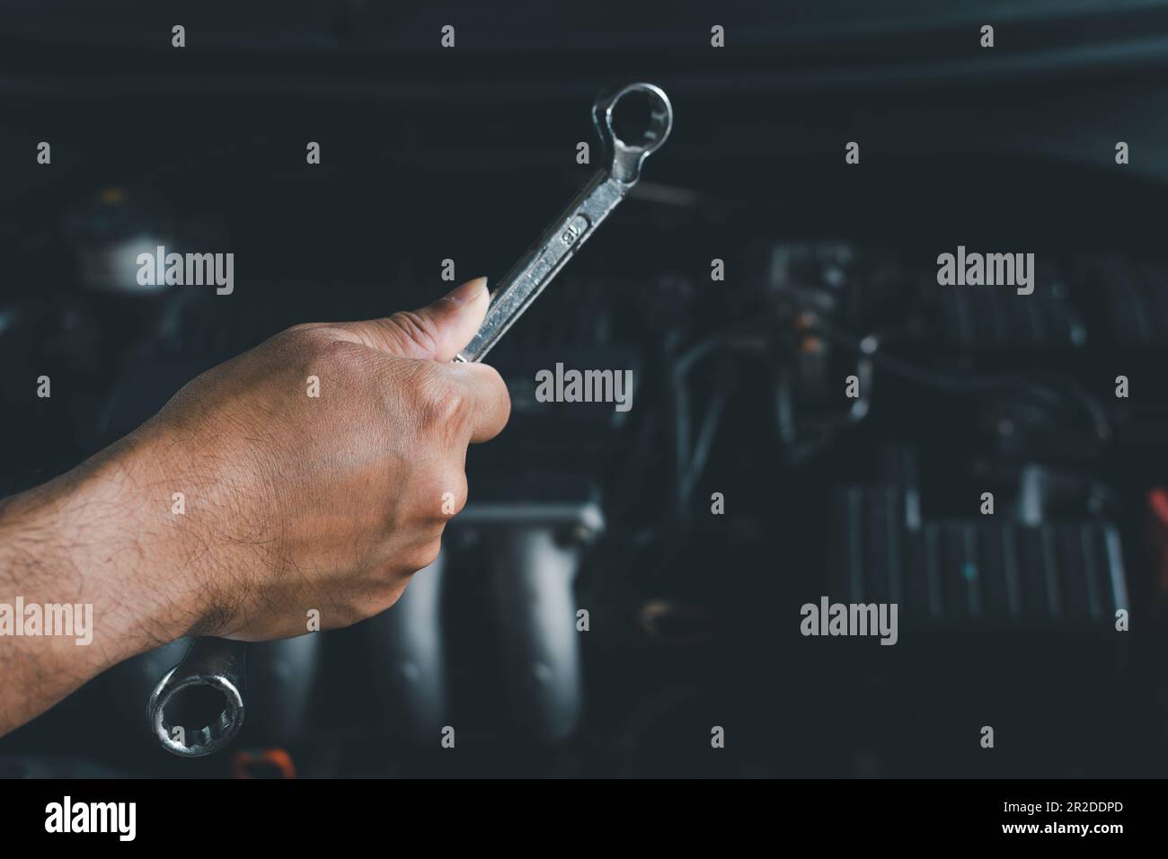 Concept of engine maintenance Mechanic holds a wrench to tighten the ...