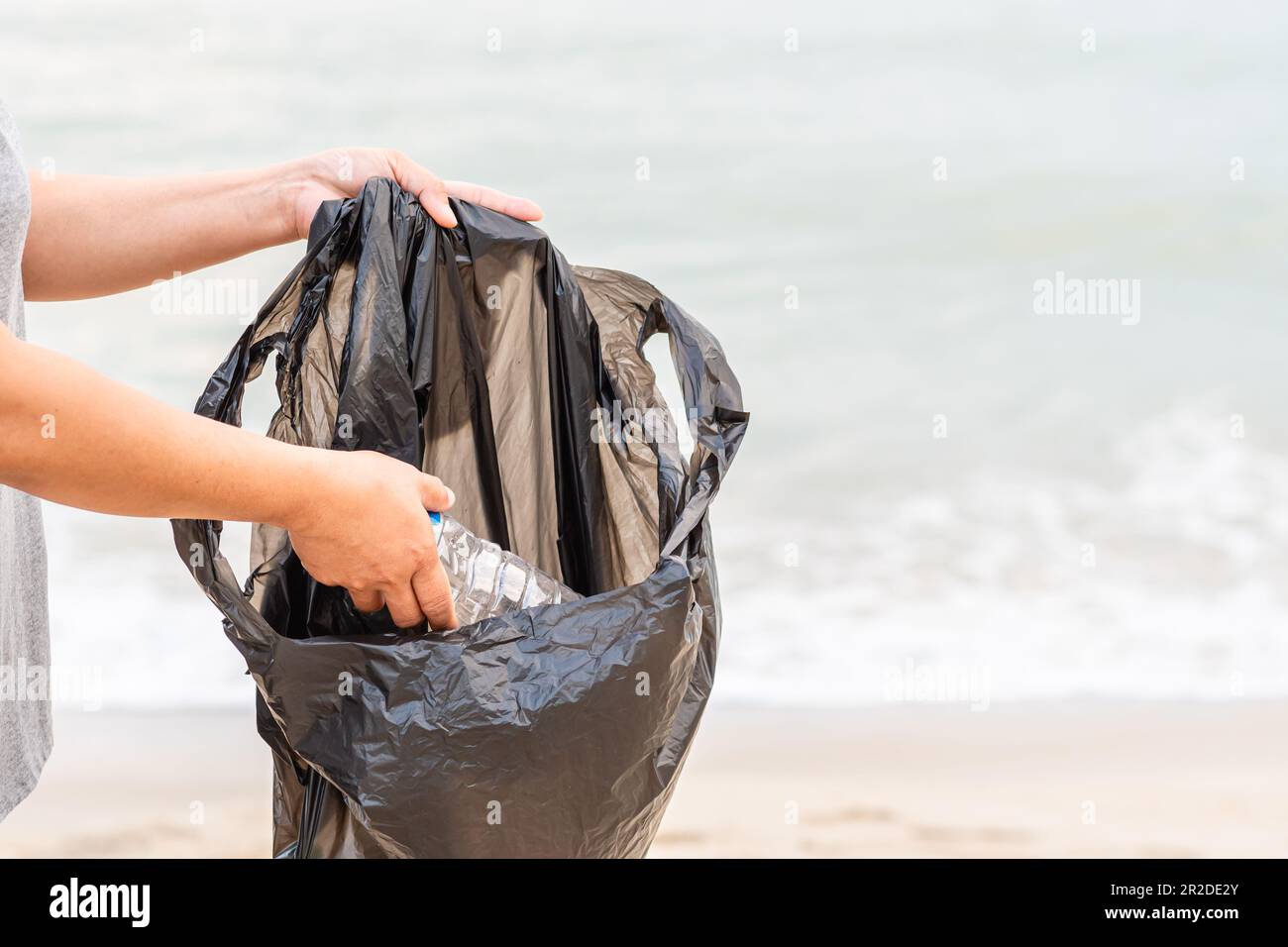 Woman cleaning by picking up plastic bottles at the beach Eco concept ...
