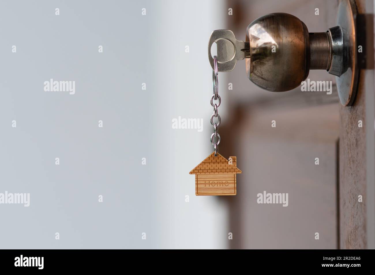 House key with house keyring in the keyhole on the wooden door. The ...