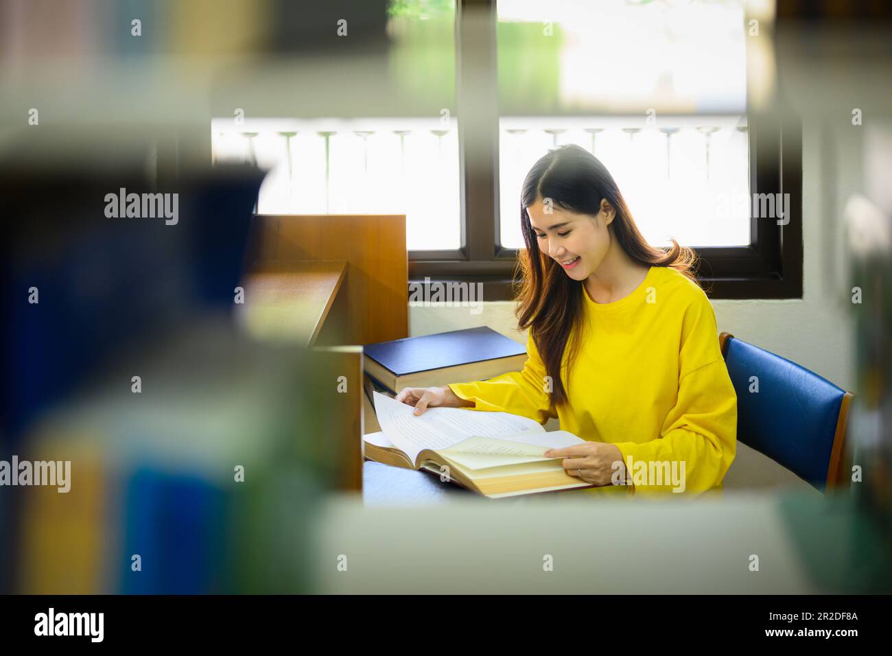 Concentrated female student reading book, doing class assignment in ...
