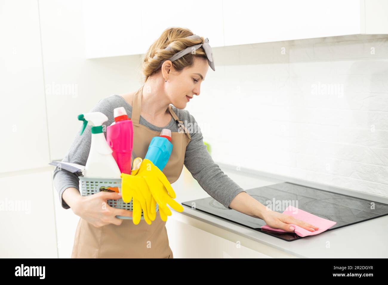 Woman cleaning and polishing the kitchen worktop with a spray detergent ...
