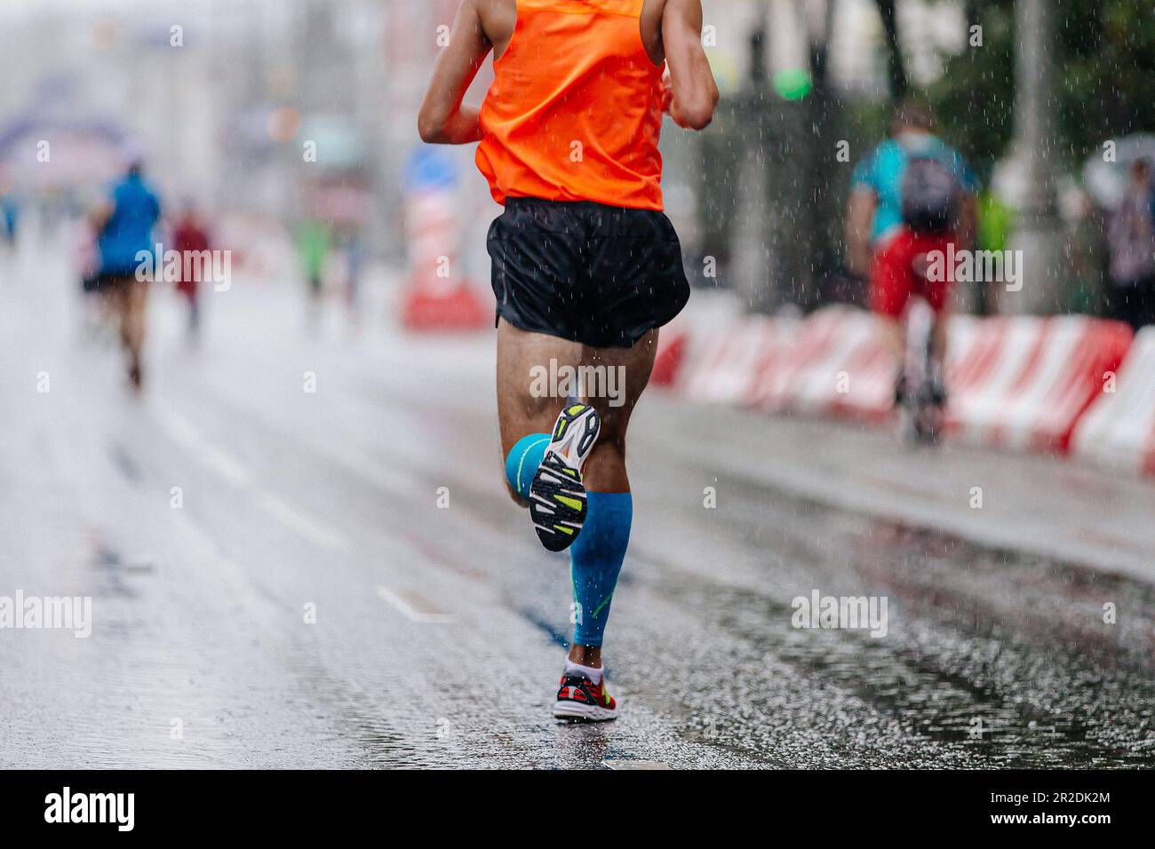 rear view runner athlete run marathon race on rain, in blue compression ...