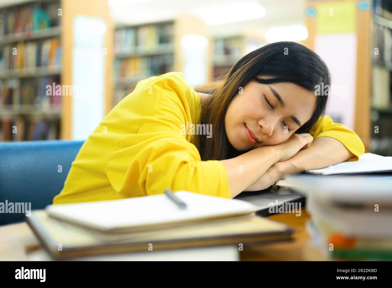 Tired asian female student taking a nap in the university library ...