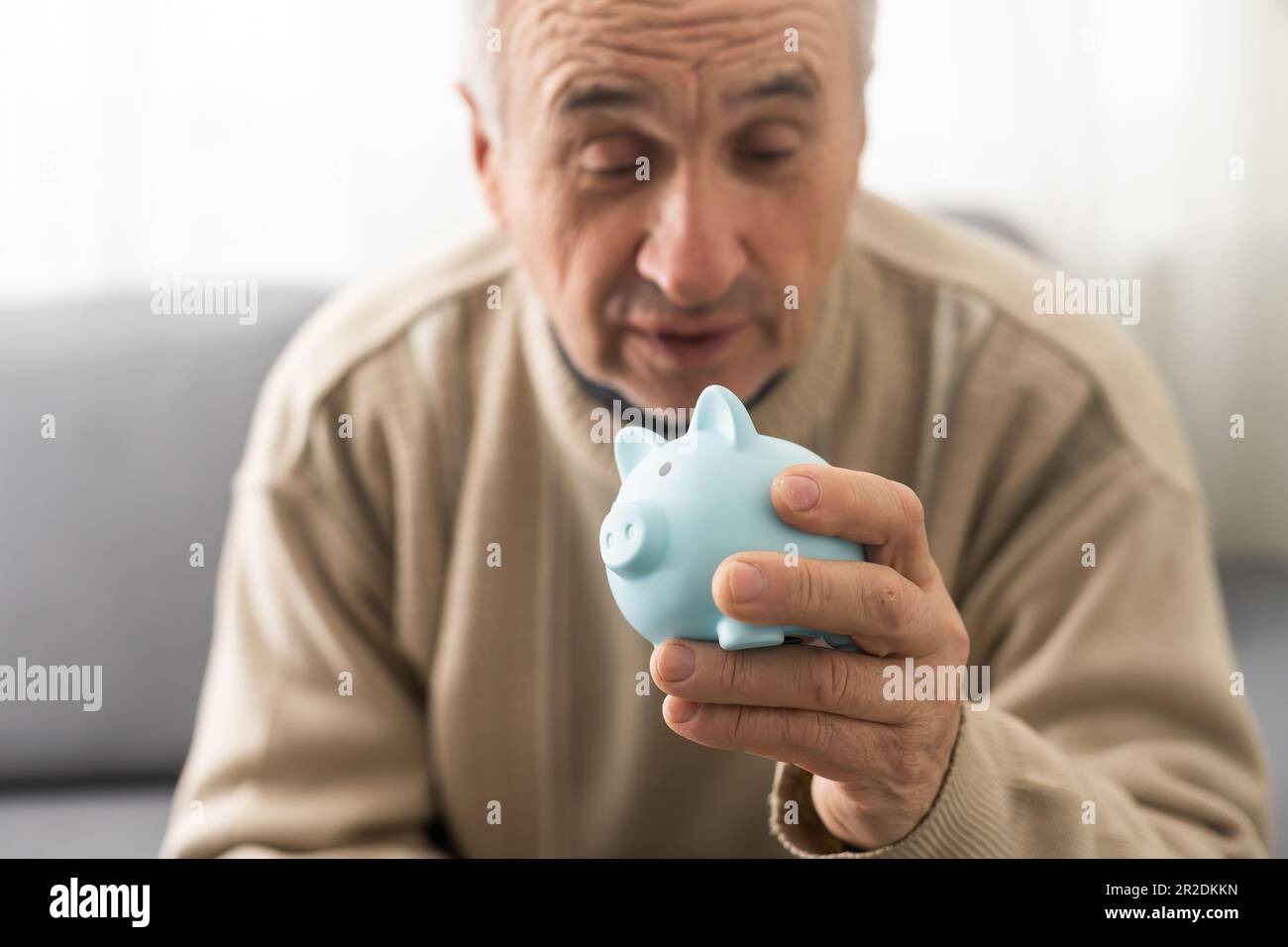 Senior caucasian man holding piggy bank with glasses depressed and ...