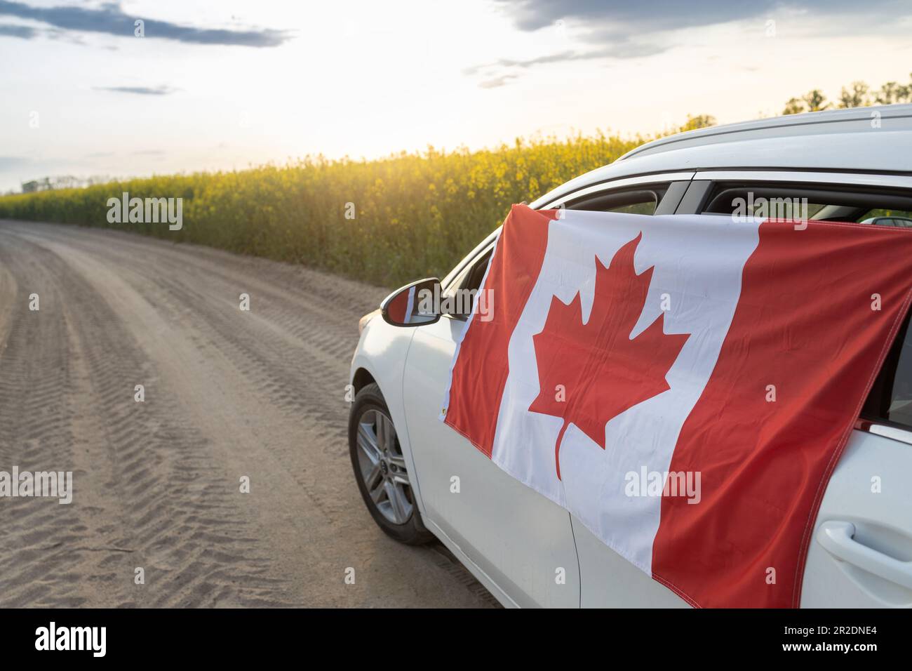 Canadian flag hanging on side of car against backdrop of setting sun ...
