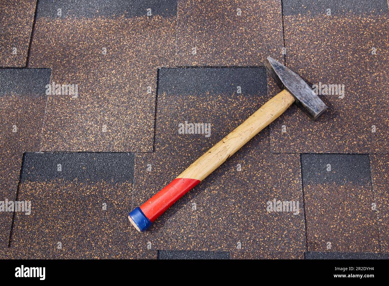 Hammer on the soft roof tiles on the roof of the building. Copy space ...