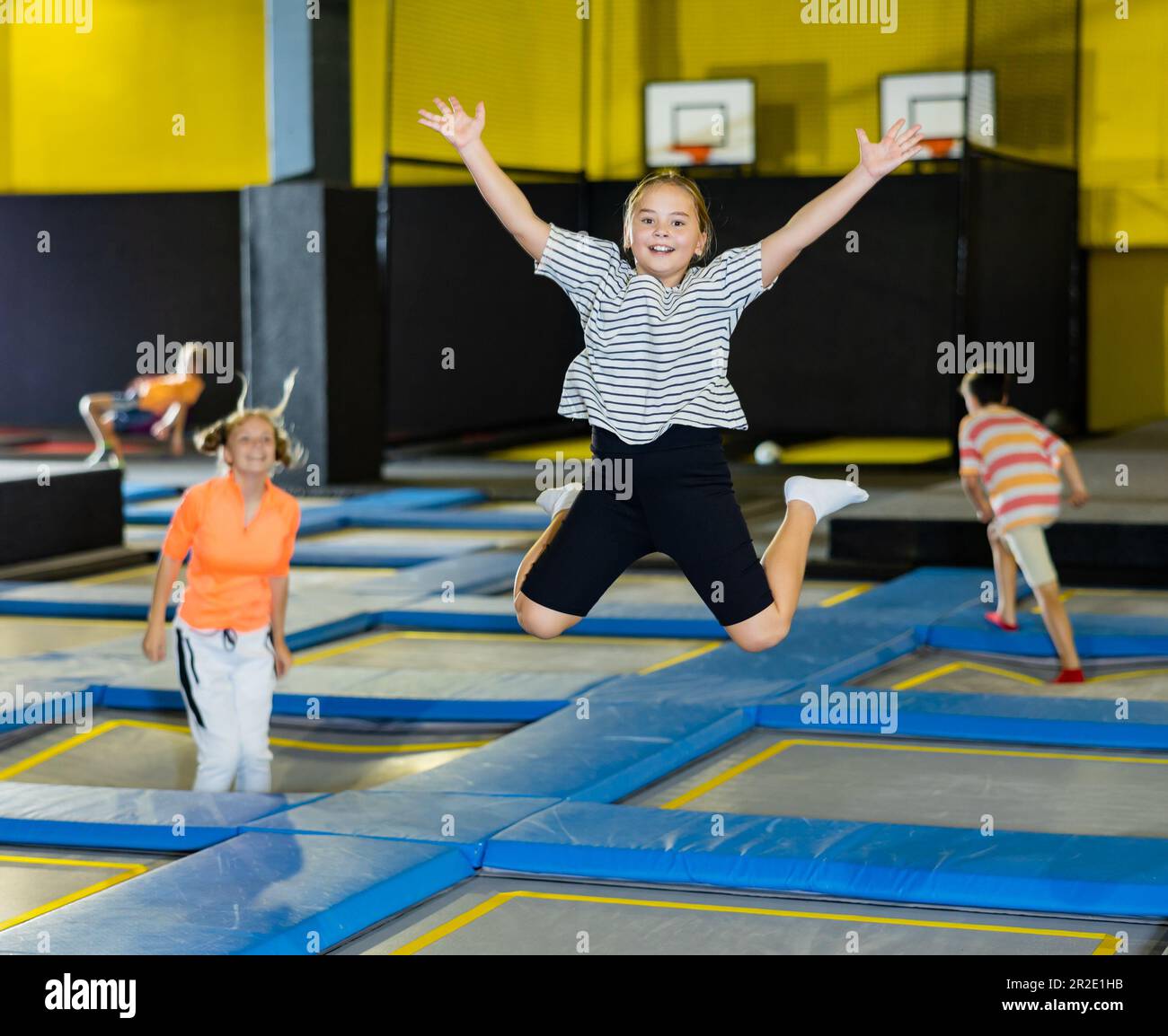 Tween girl bouncing on trampoline in indoor amusement park Stock Photo ...