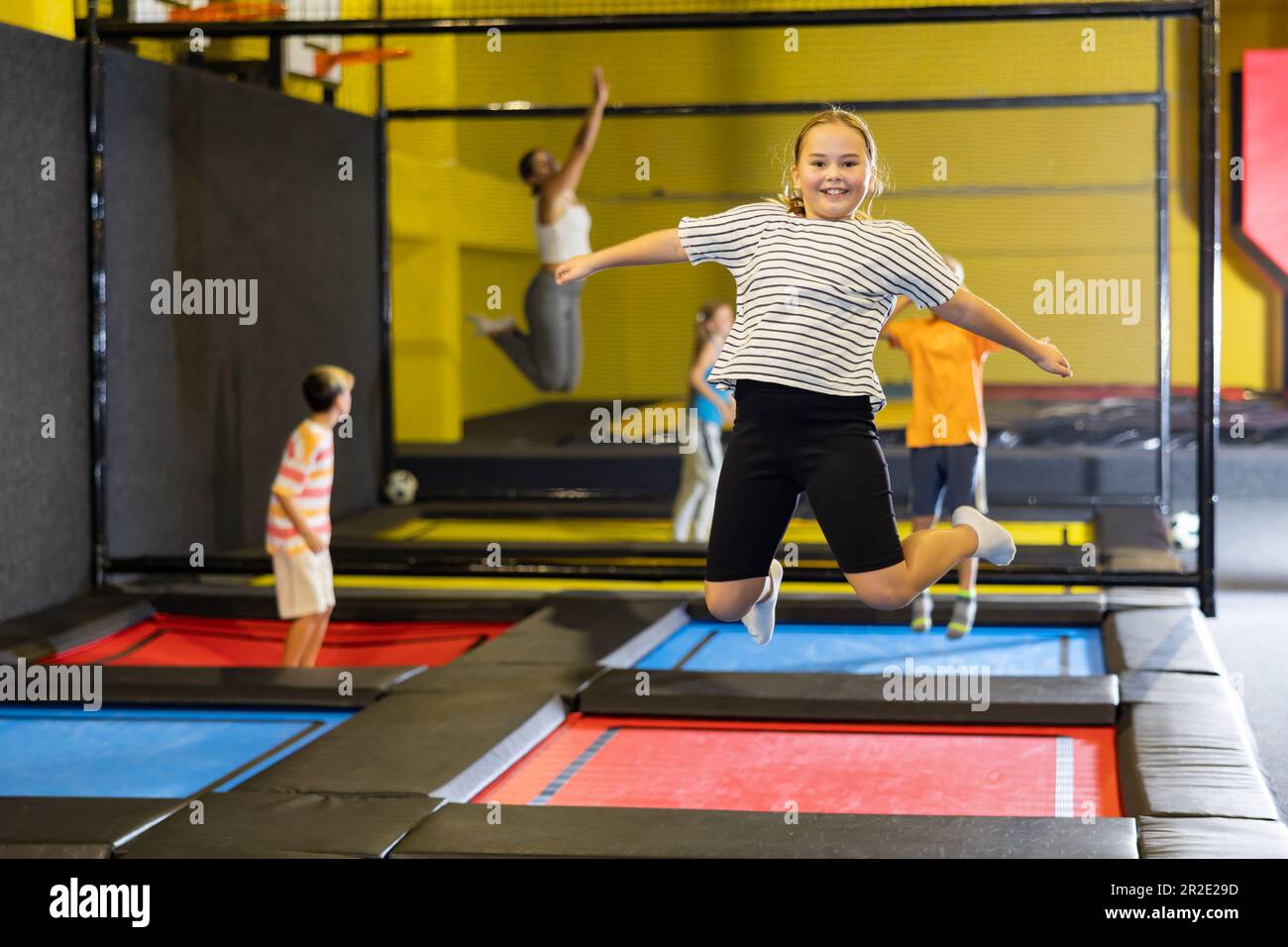 Happy cute little girl jumping on trampoline indoors Stock Photo - Alamy