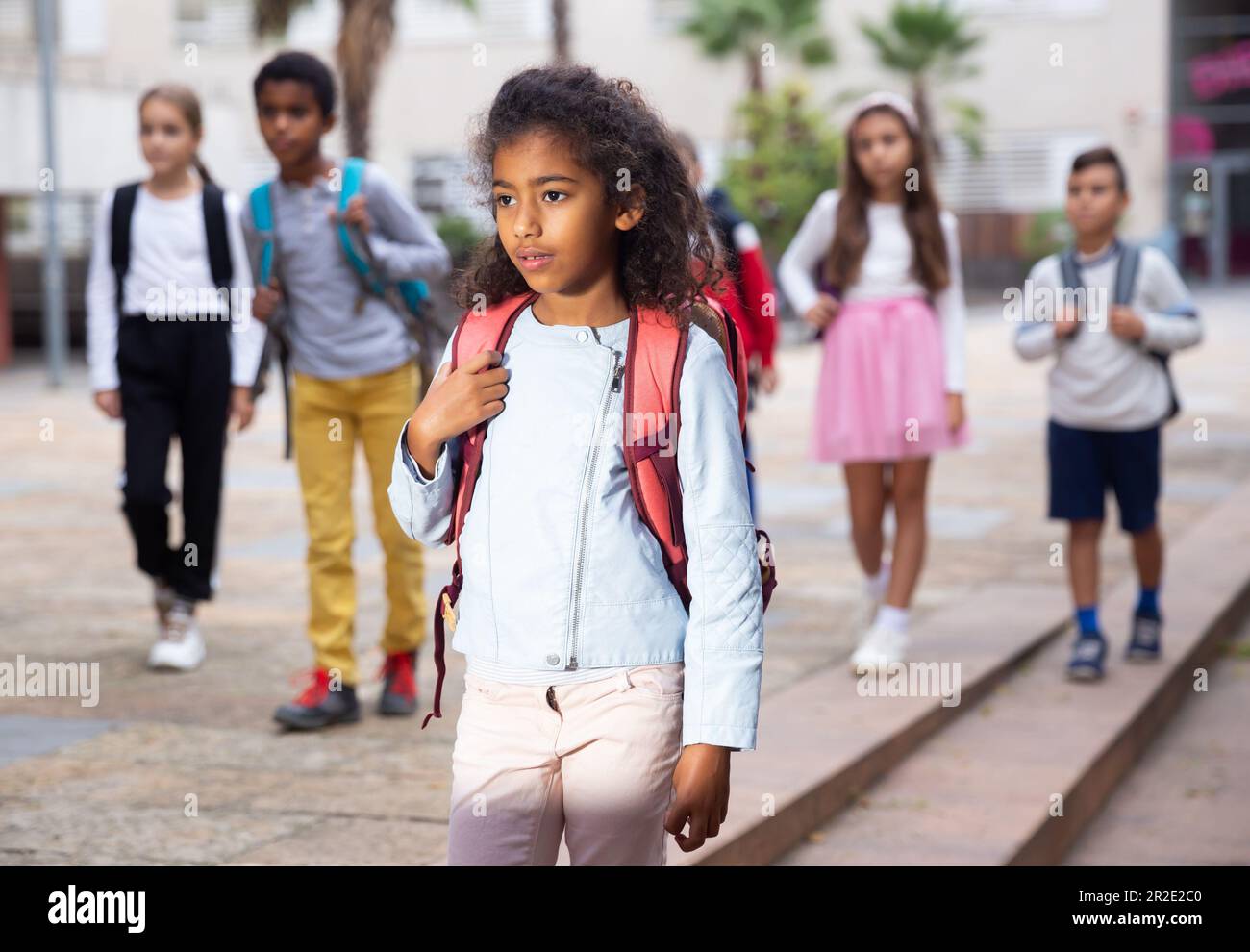 Curly tween girl walking to school campus after lessons Stock Photo - Alamy