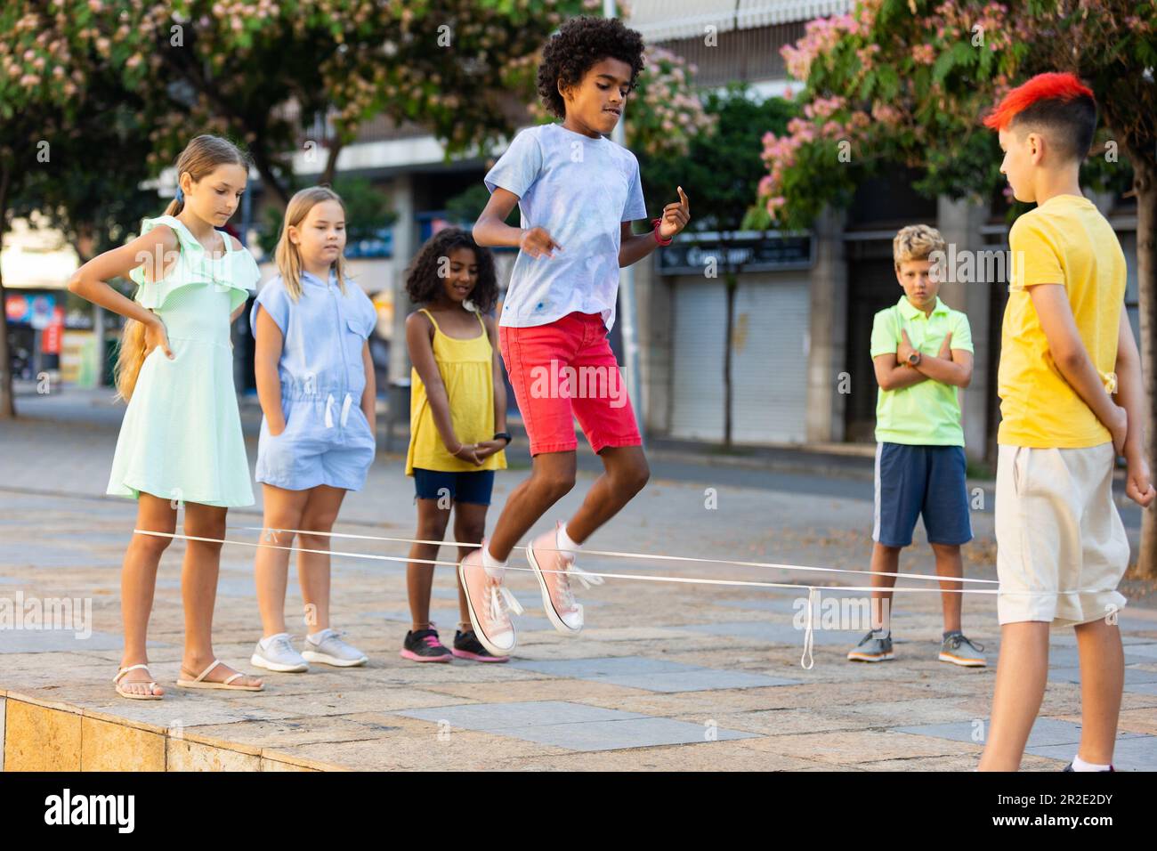 Kids playing with chinese jumping rope outdoors Stock Photo - Alamy