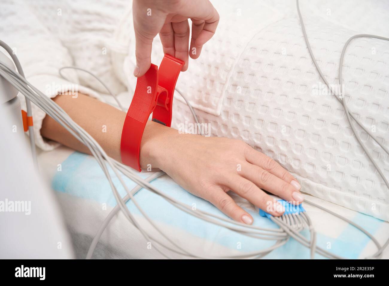 Female diagnostician attaches sensors to the patients arms for an ECG ...