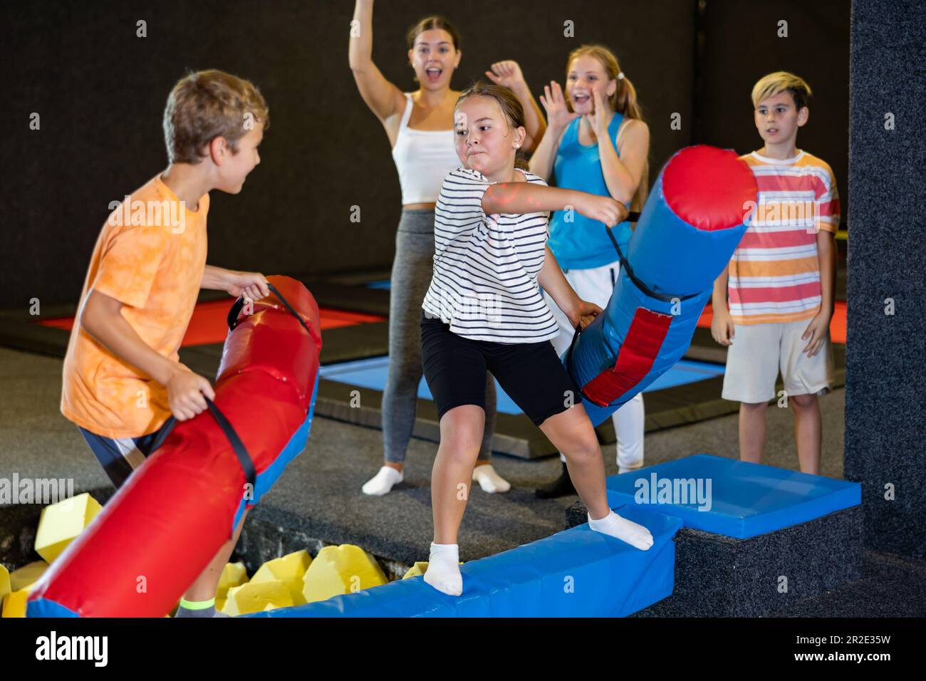 Children having funny wrestling by inflatable logs in indoor amusement ...