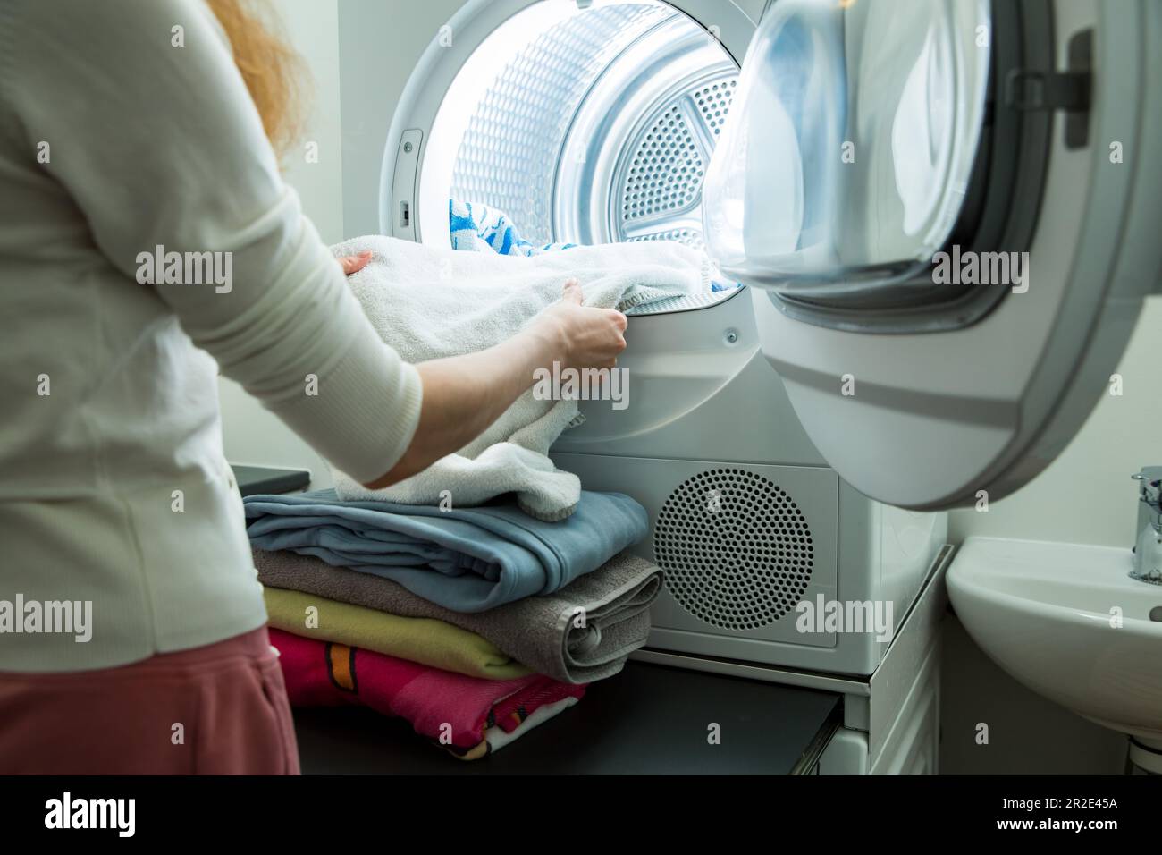 Woman doing laundry. Dryer machine in a Landry room at home drying ...