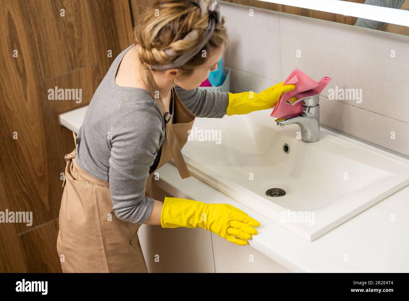 Woman cleaning and polishing the kitchen worktop with a spray detergent, housekeeping and ...