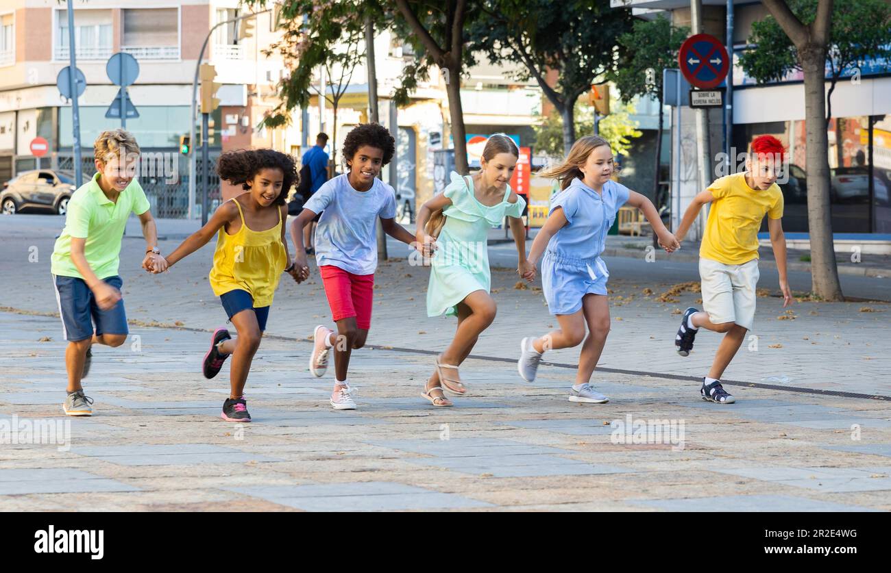 Happy children running together hand in hand through streets Stock ...