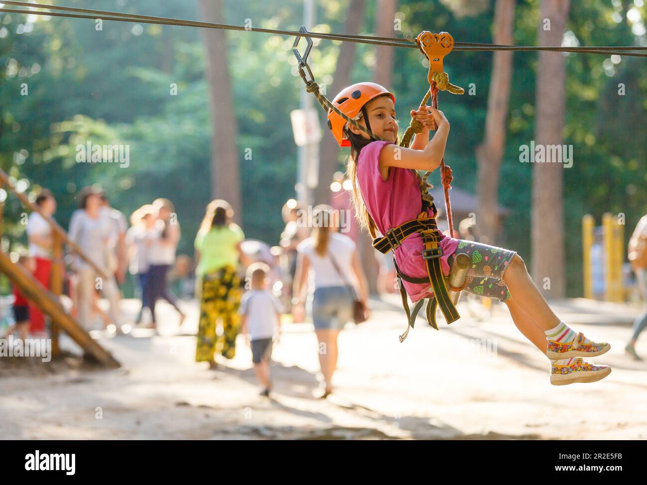 Happy school girl enjoying activity in a climbing adventure park on a ...