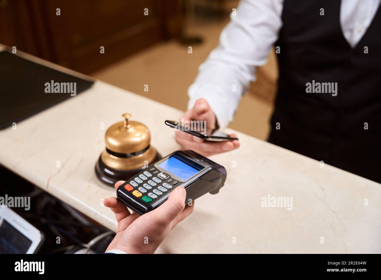 Male guest paying contactless while manager holding credit card machine ...