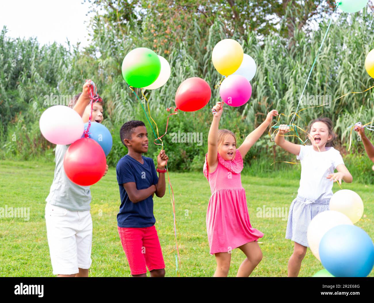 Happy tweens with balloons on green meadow in summer park Stock Photo ...