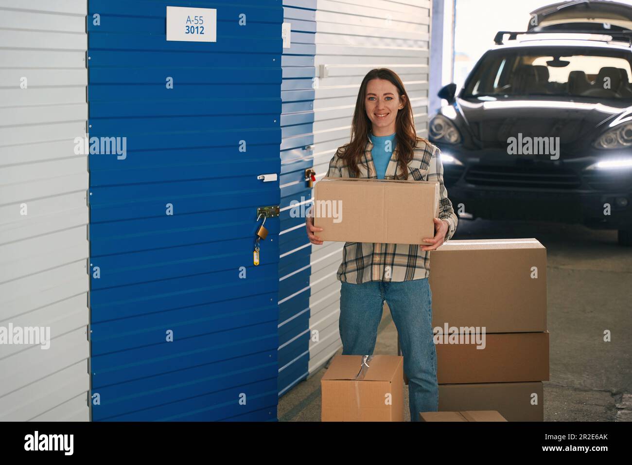 Young woman with big cardboard boxes into warehouse with self storage ...