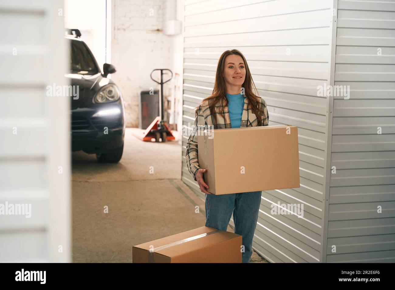 Young lady with big cardboard boxes into warehouse with self storage ...