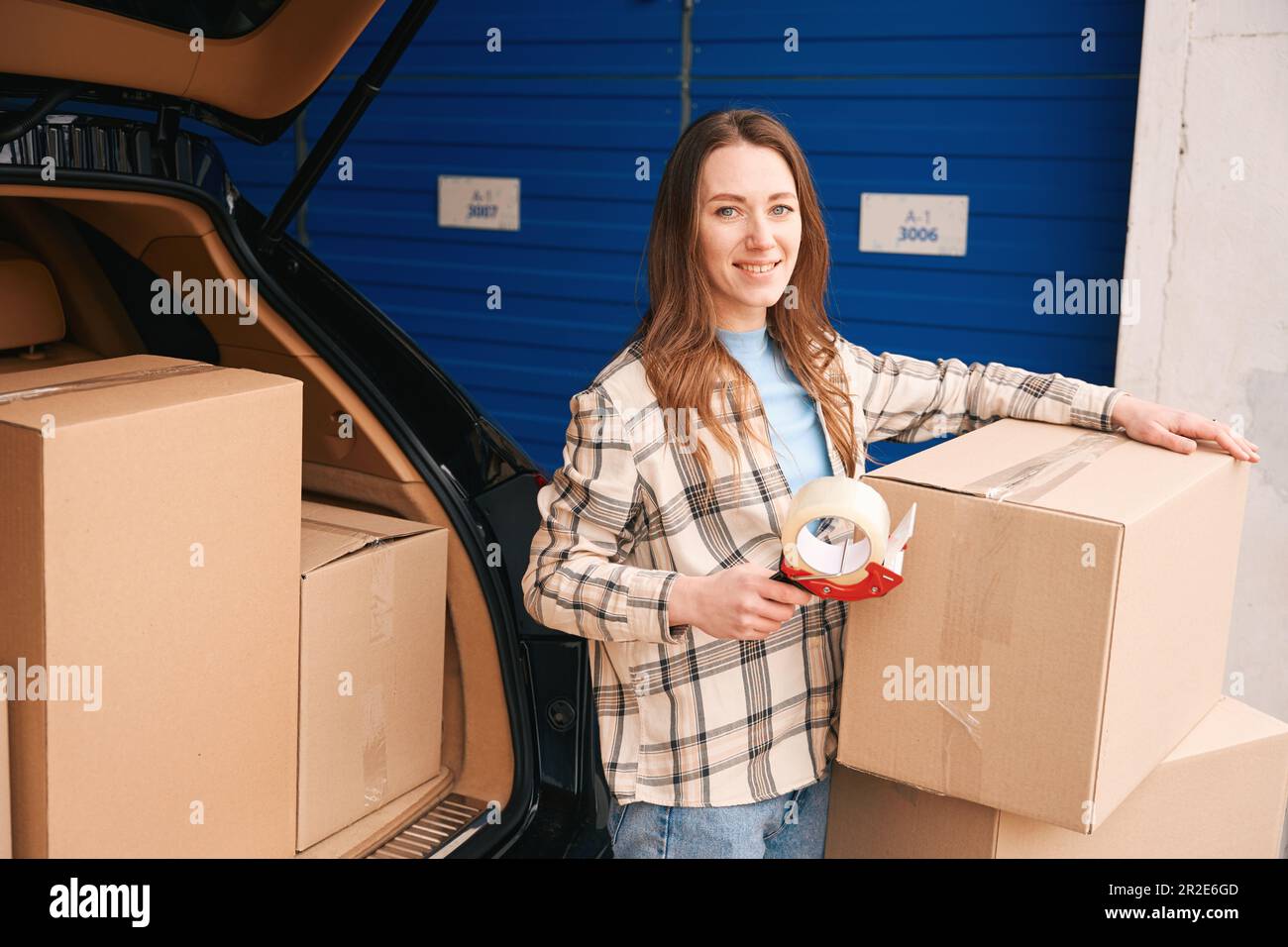 Young woman with big cardboard boxes and scotch in warehouse Stock ...