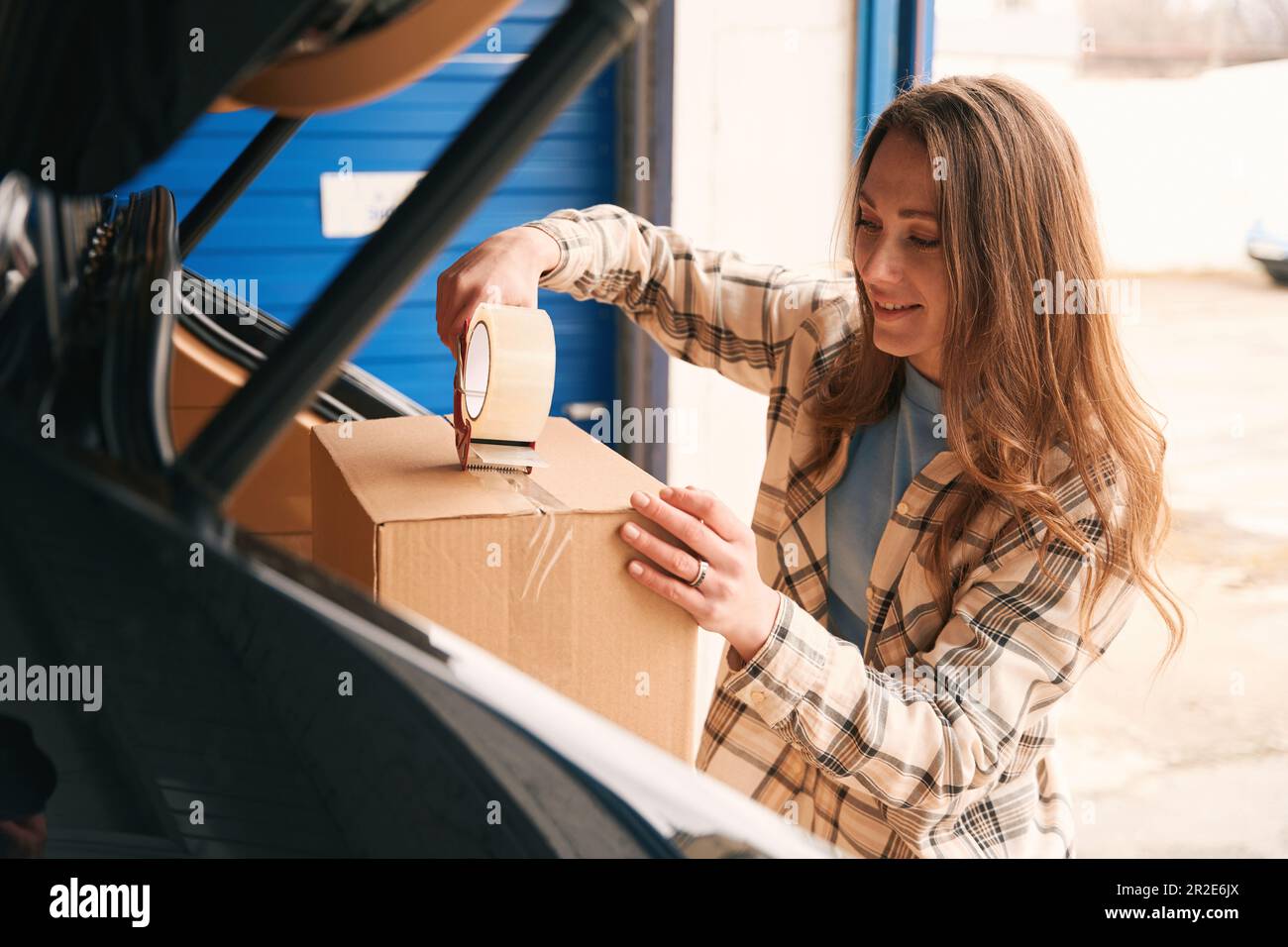 Smiling woman with big cardboard boxes and scotch into warehouse Stock ...