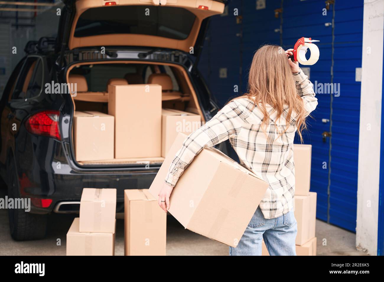 Back view of woman with big cardboard boxes and scotch in hand Stock ...