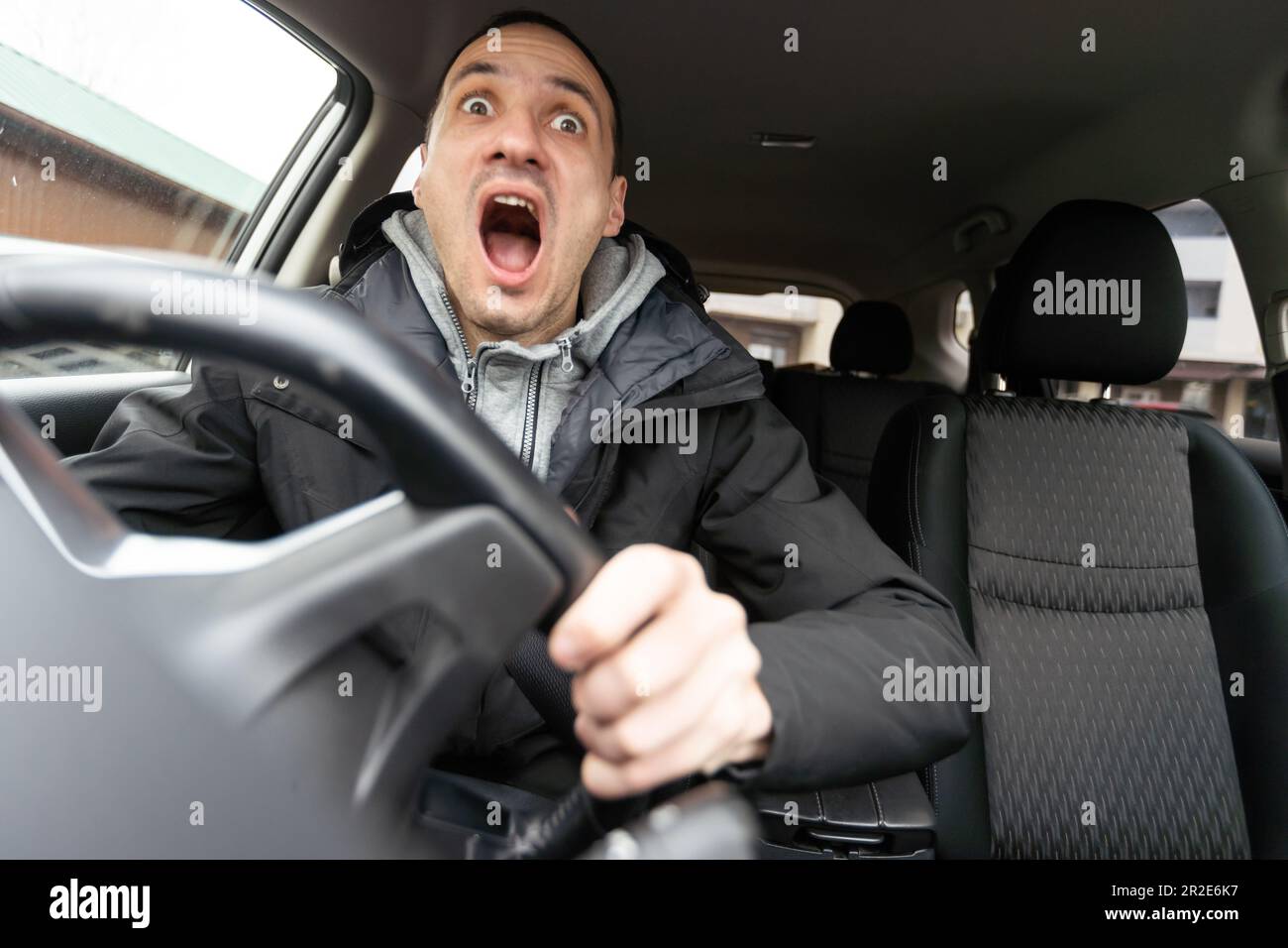 Angry man driving a car. Male driver gesturing and shouting behind the ...