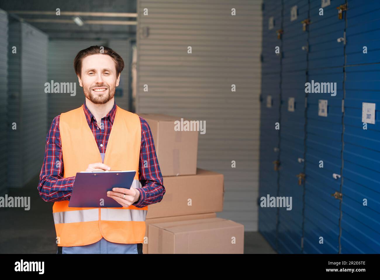 Waist-up of young man in work clothes into warehouse with self storage ...