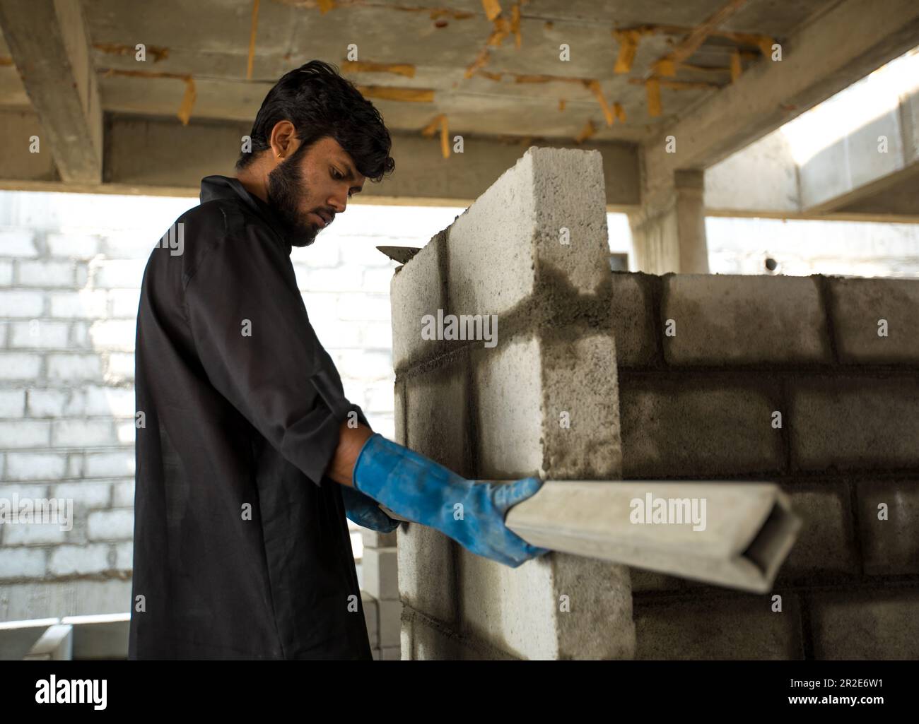 A worker may be seen using a level to inspect a brick wall Stock Photo ...