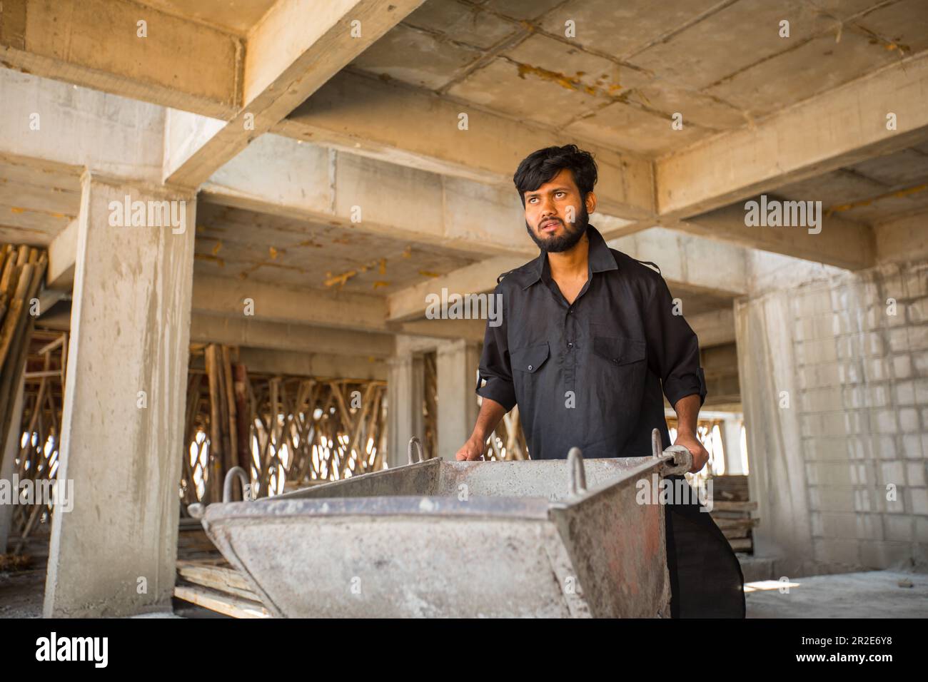 A construction worker moves concrete into a wheelbarrow at a building ...