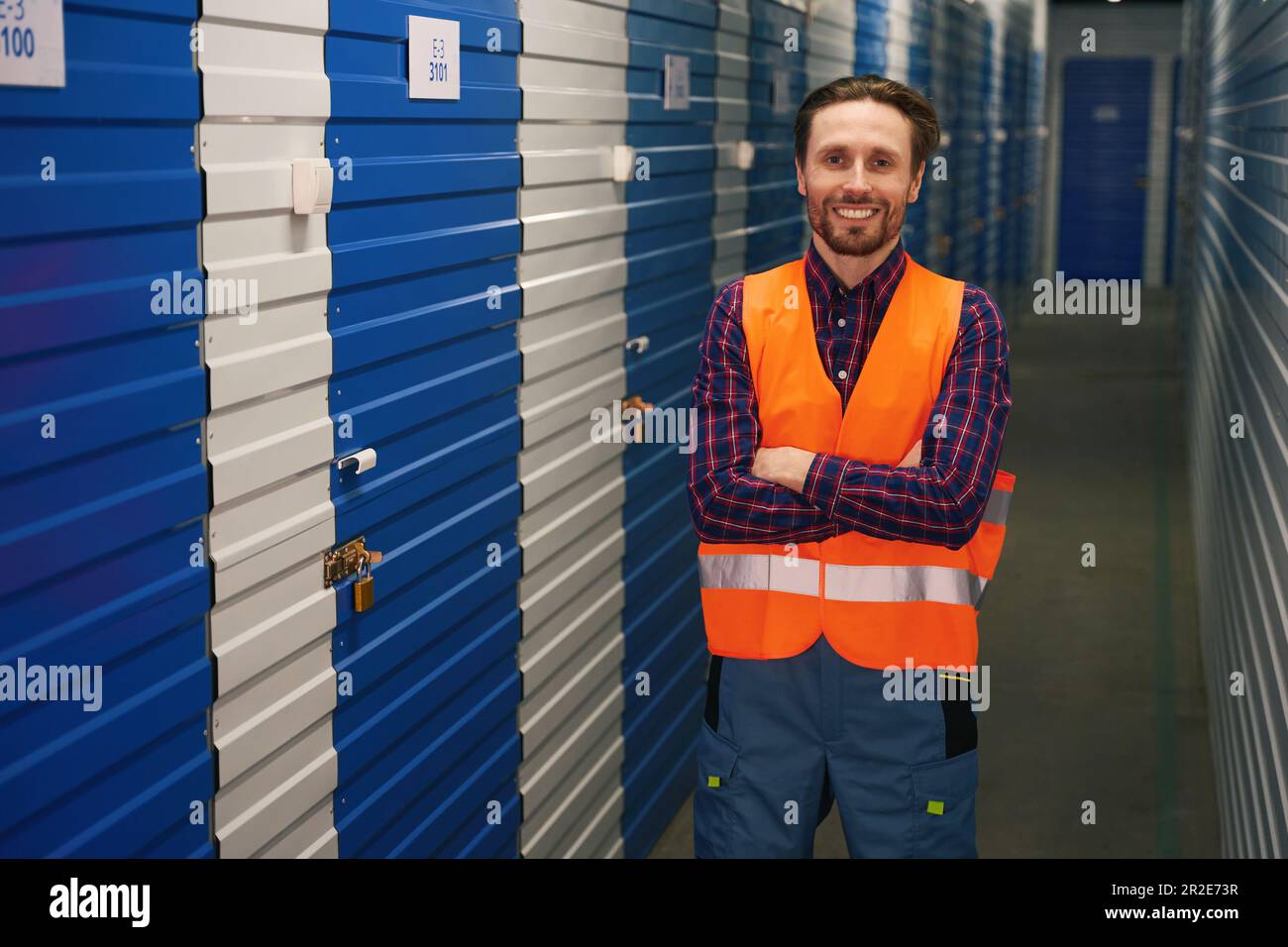 Waist-up of young man in work clothes into warehouse with self-storage ...