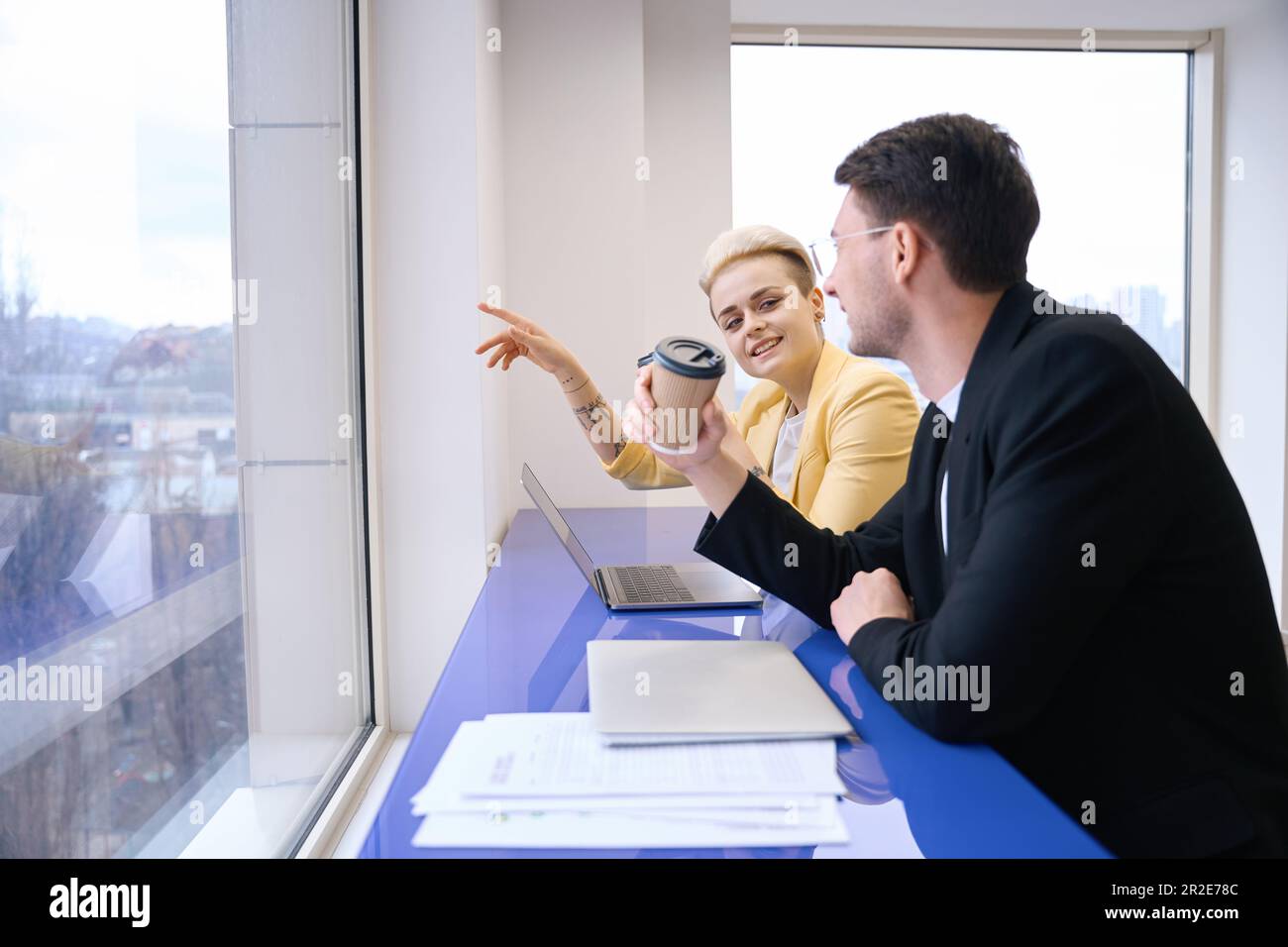 Office workers resting looking at big window Stock Photo - Alamy
