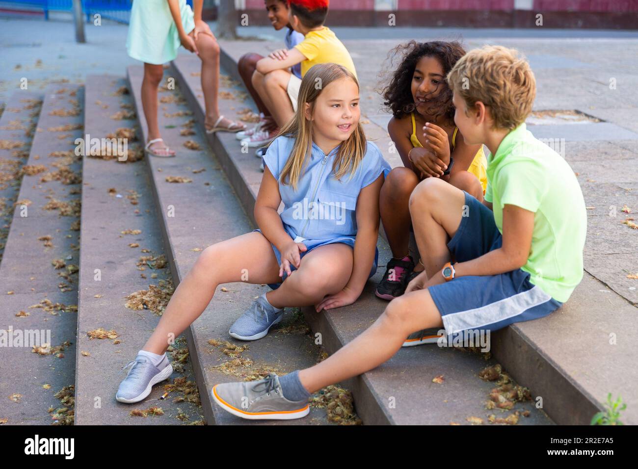 Group of kids sitting on stairs outdoors and talking Stock Photo - Alamy
