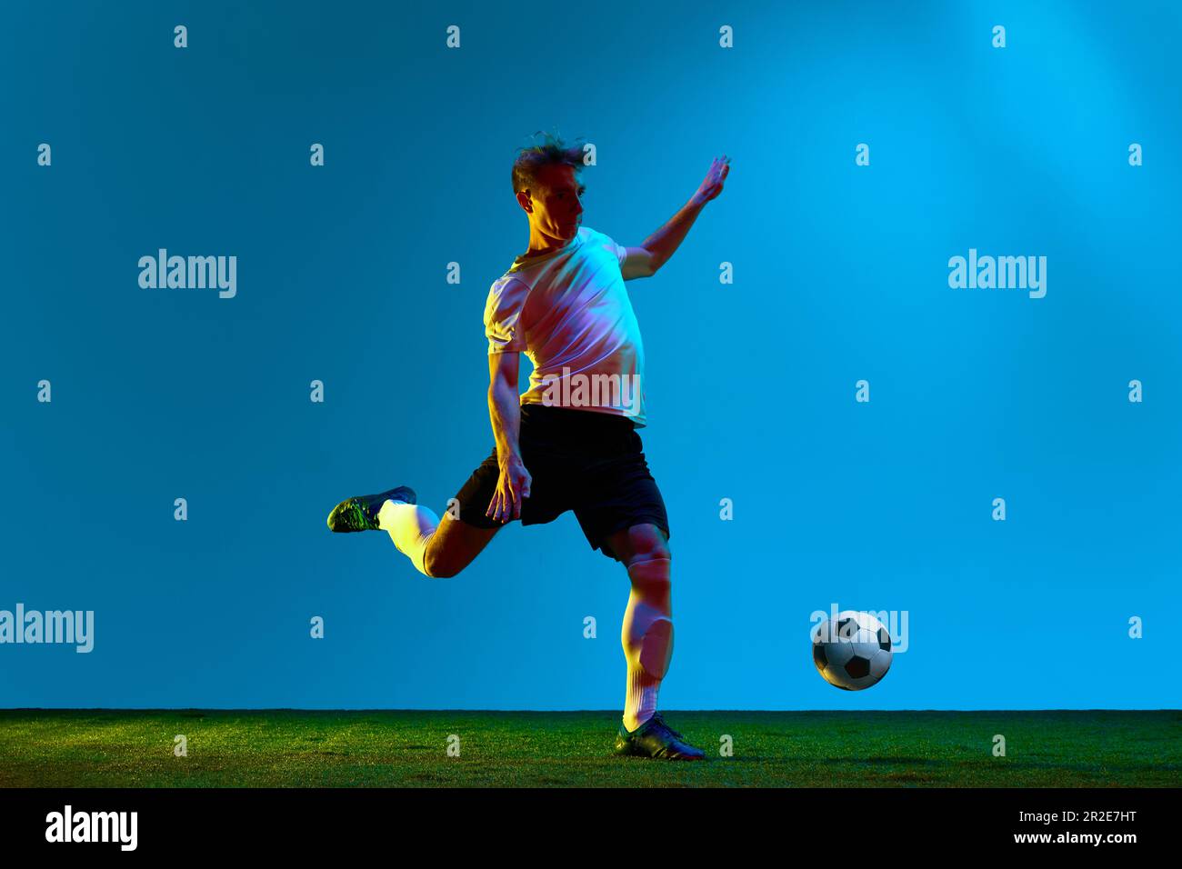 Portrait with young guy, man football soccer player kicking ball in ...