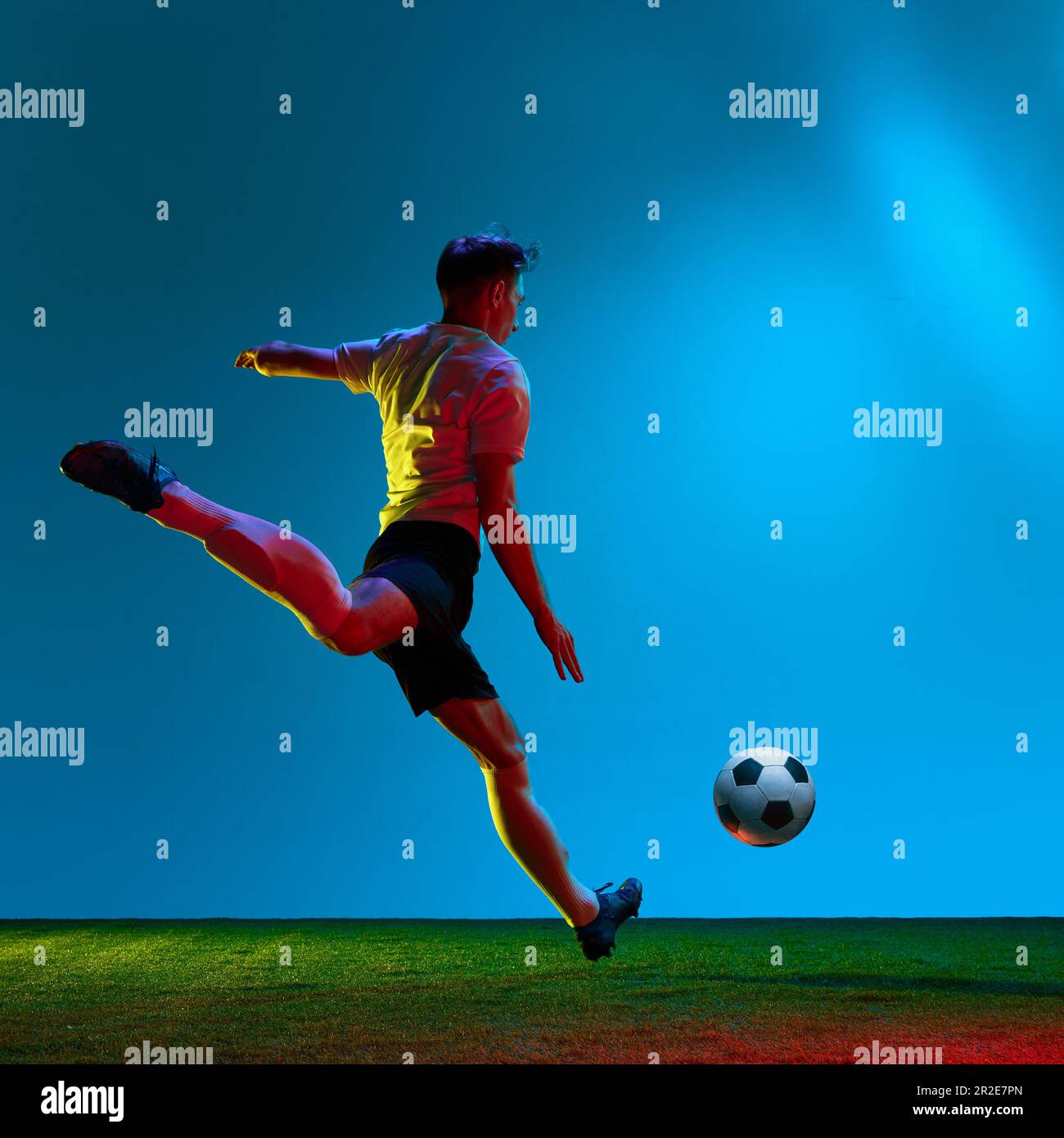 Dynamic portrait of soccer, football player in sports uniform kicking ...