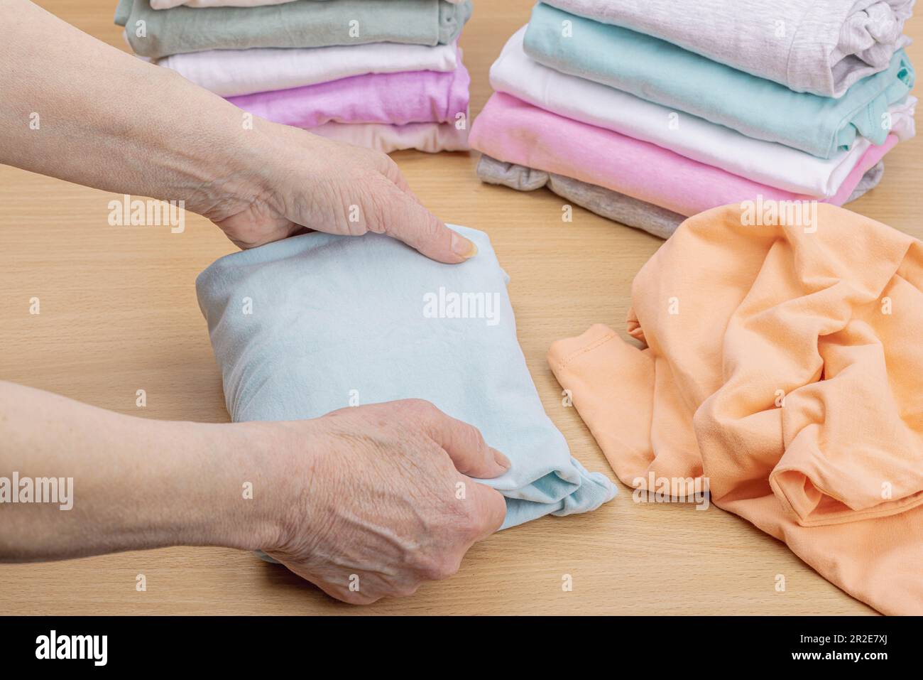 Women's hands fold clean clothes. Vertical storage of clothing in the ...