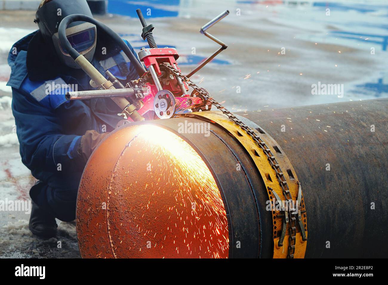 Welder in mask cuts large-diameter pipe with autogenous gun and sparks ...