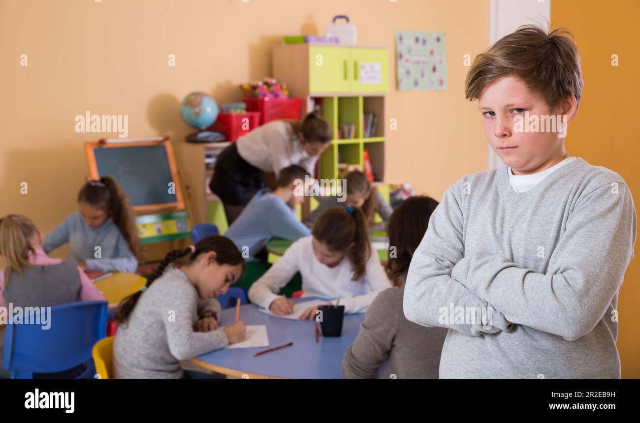 Upset schoolboy standing, boys and girls in classroom Stock Photo - Alamy